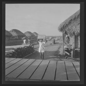 Man carrying a chest on his head toward a boardwalk at Aiyetoro